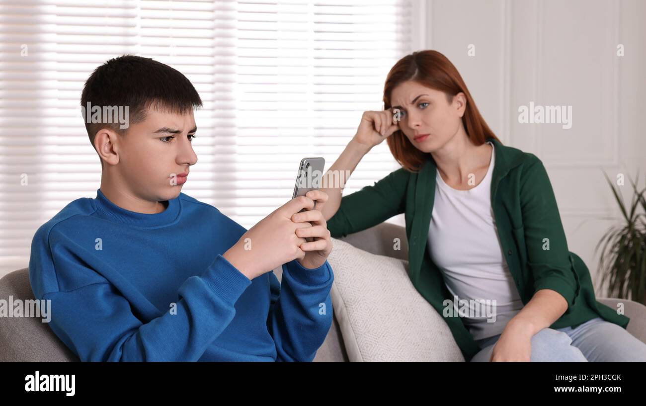 Boy using smartphone and ignoring his upset mother at home. Teenager problems Stock Photo - Alamy
