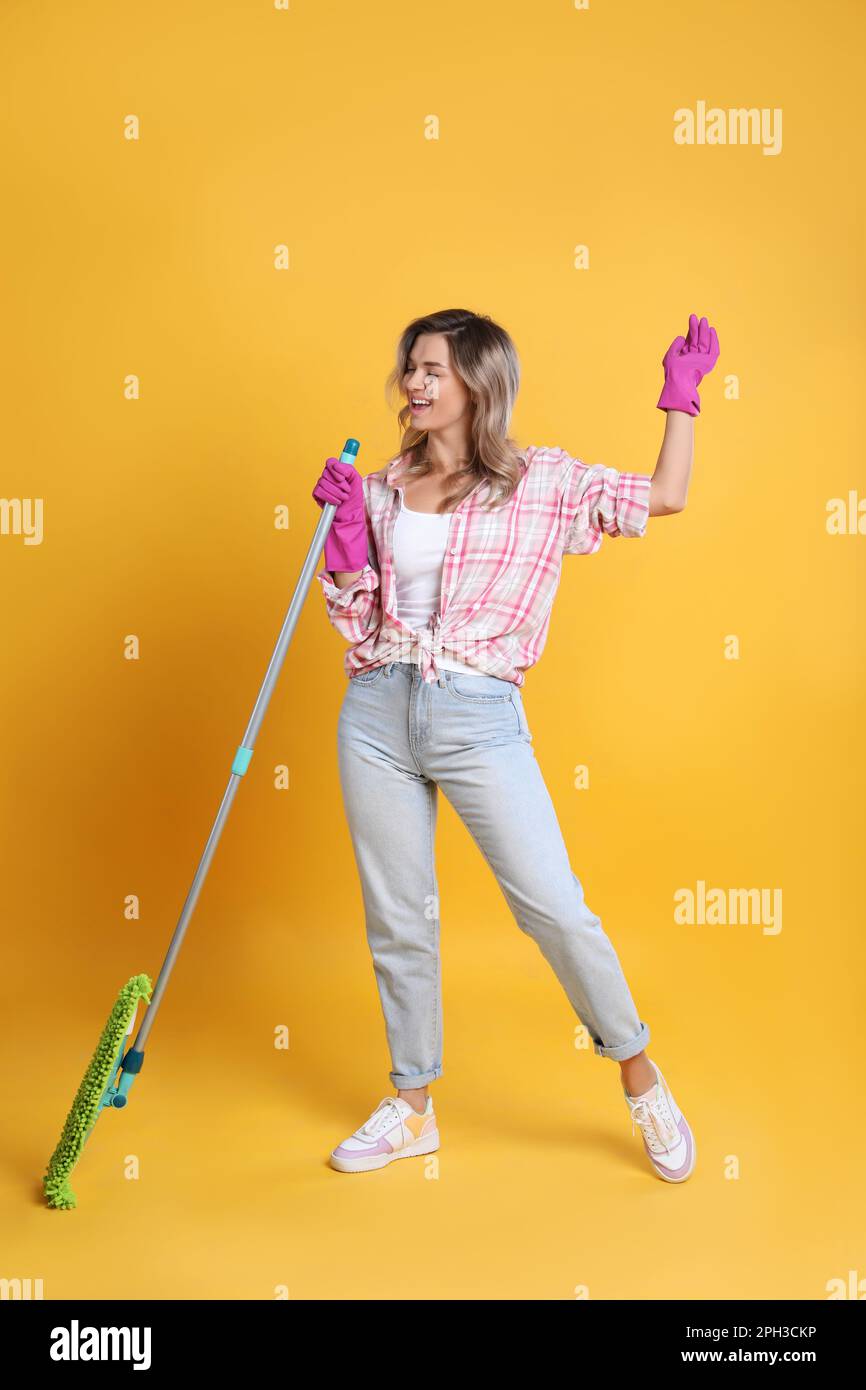 Beautiful young woman with mop singing on orange background Stock Photo ...