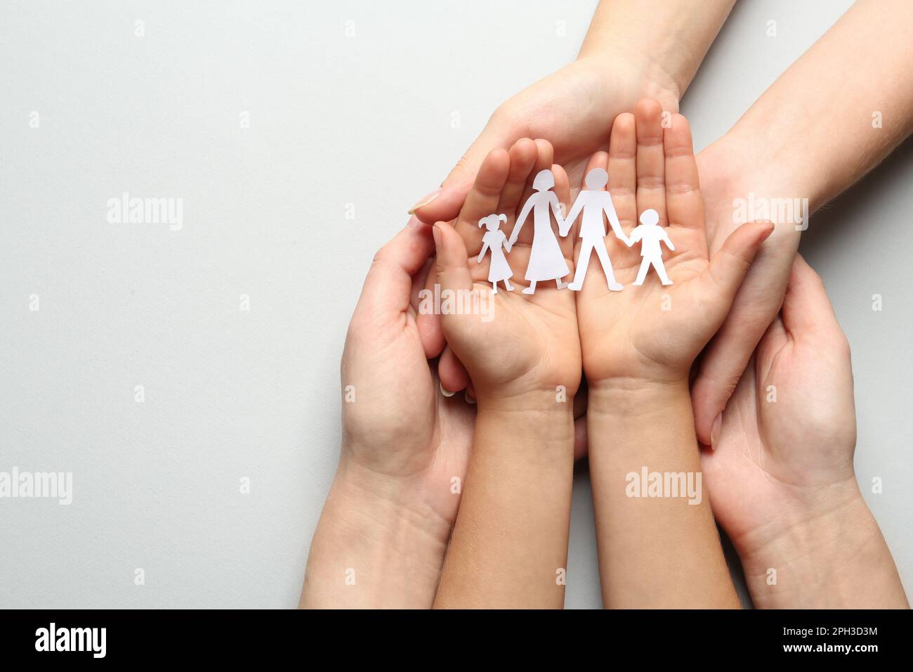 Parents and child holding paper cutout of family on light background ...