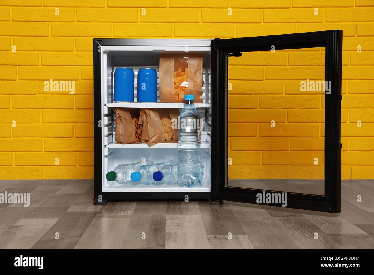 Mini bar filled with food and drinks near yellow brick wall indoors ...