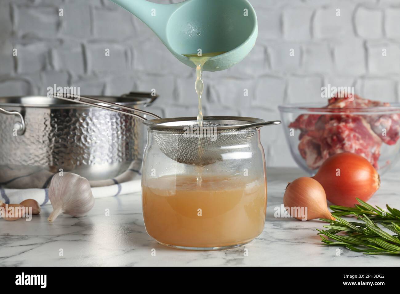 Straining delicious broth through sieve on white marble table Stock ...