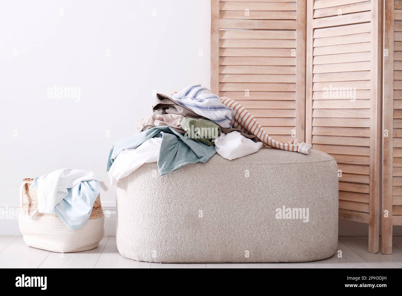 Messy pile of dirty clothes on ottoman indoors. Tidying up method Stock ...