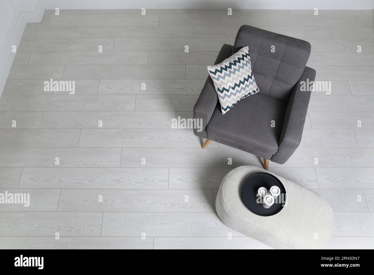 Stylish grey armchair and pouf with candles in room, above view ...