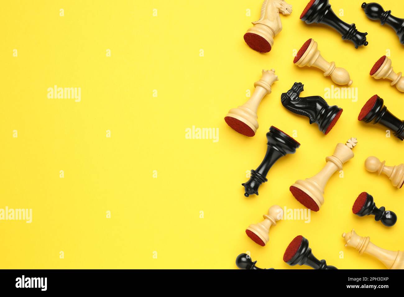 Many different chess pieces on yellow background, flat lay. Space for ...