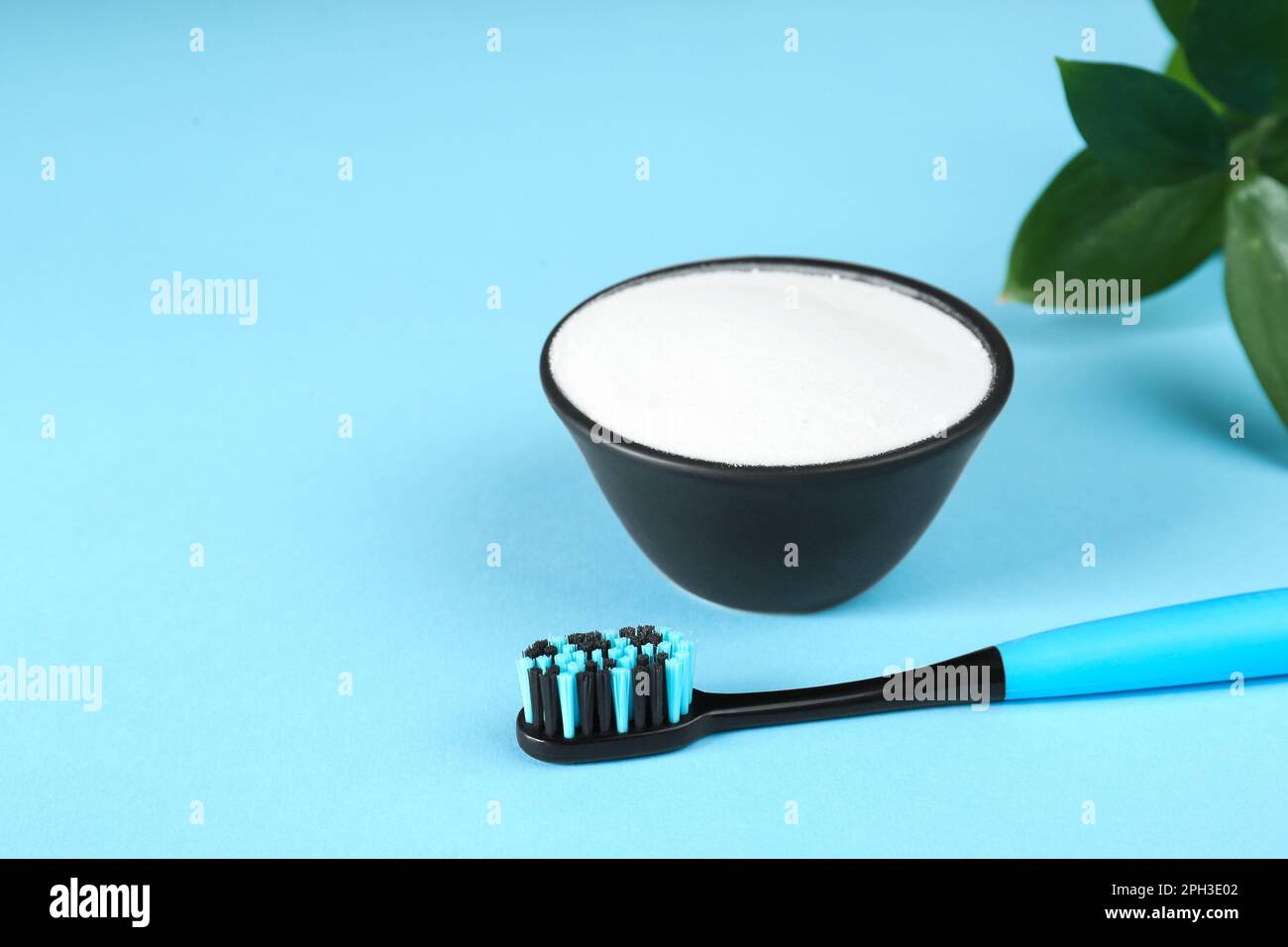 Toothbrush and bowl with baking soda on light blue background. Space ...