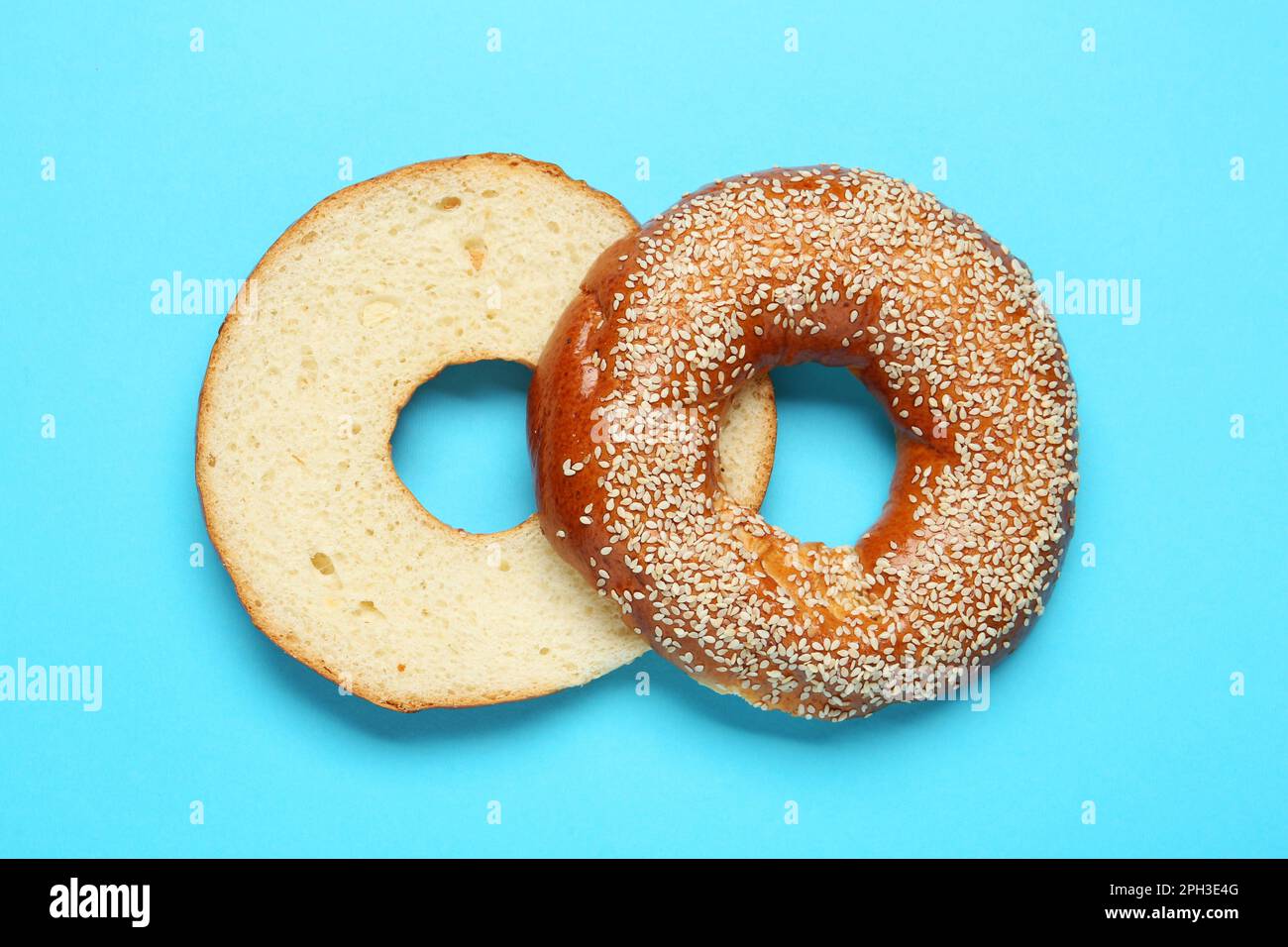 Delicious fresh halved bagel on light blue background, flat lay Stock ...