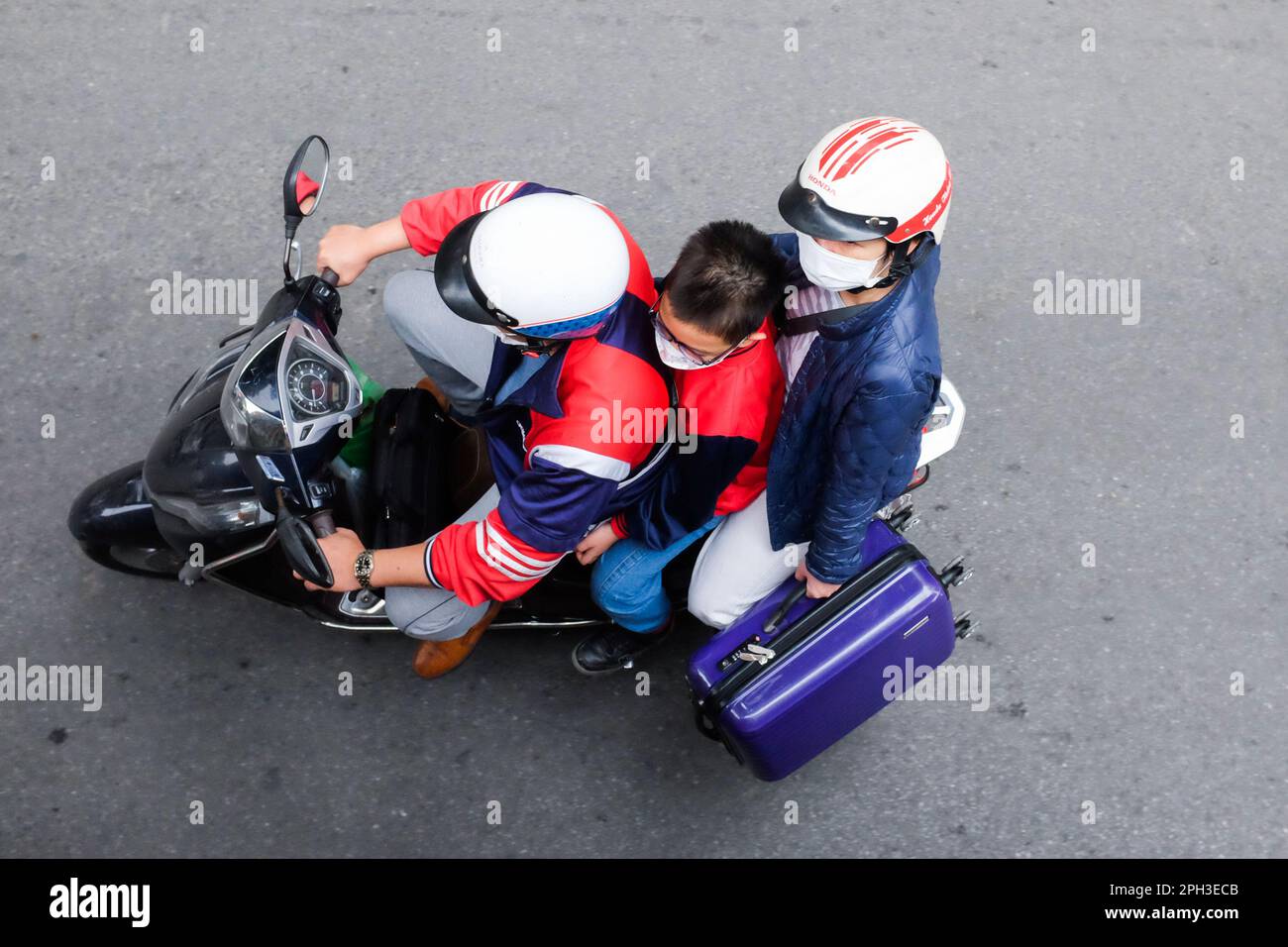A child and two adults riding on a moped in Hanoi, Vietnam, in 2023 ...