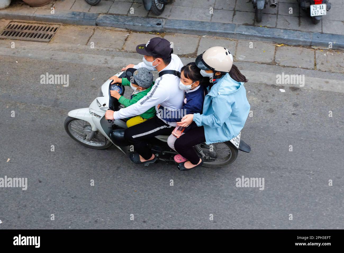 Two adults and two children riding on a moped in Hanoi, Vietnam, in ...