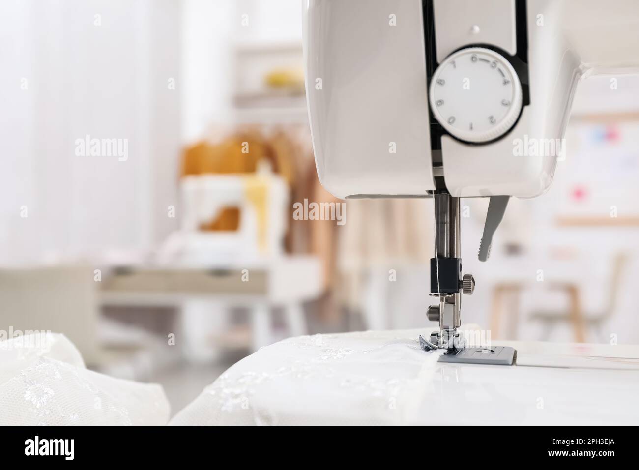 Modern sewing machine with fabric in dressmaking workshop, closeup ...