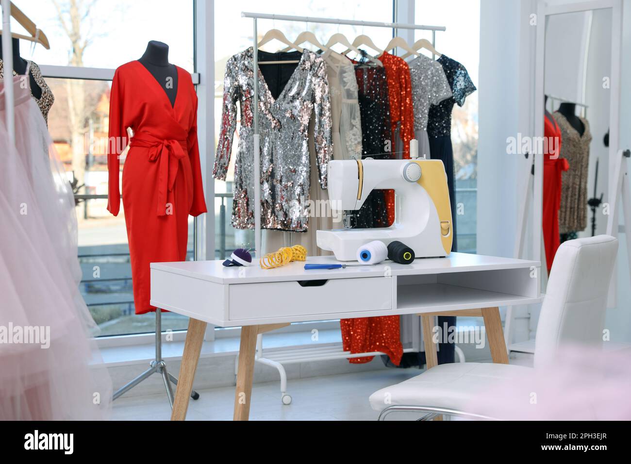 Dressmaking workshop interior with stylish female clothes and equipment ...