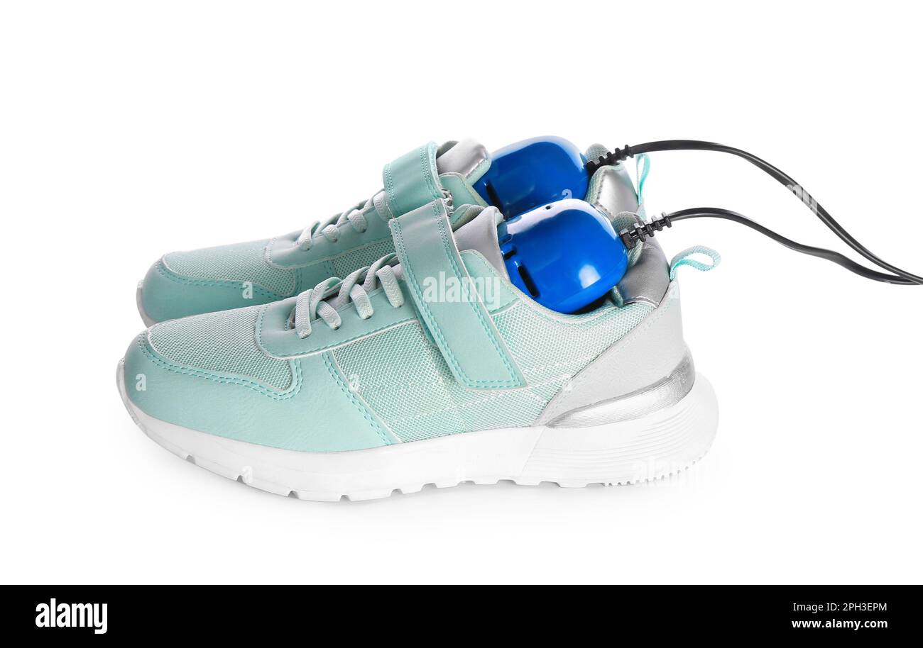 Pair of stylish shoes with modern electric footwear dryer on white ...