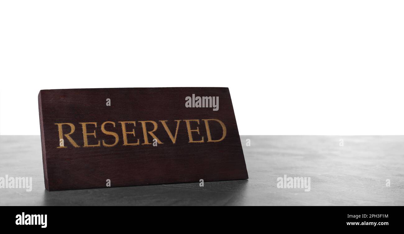 Elegant wooden sign Reserved on grey table against white background ...