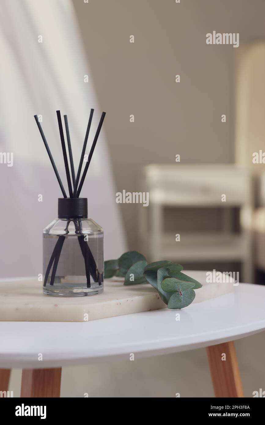 Aromatic reed air freshener and eucalyptus branch on white table in ...