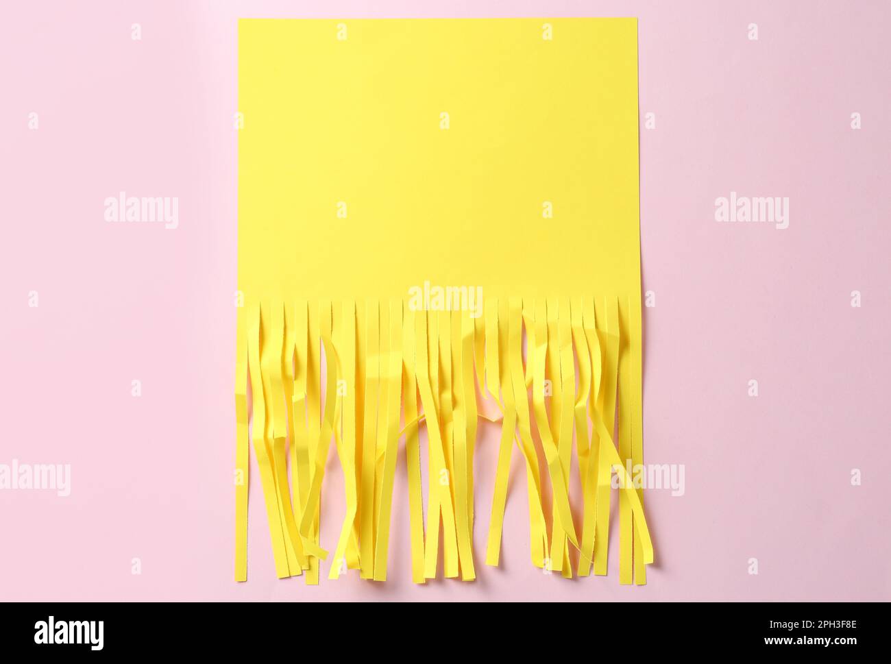 Half shredded sheet of yellow paper on pink background, top view Stock ...