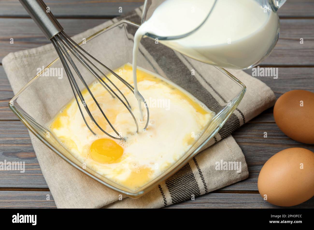 Adding milk to whisked eggs at wooden table, closeup Stock Photo - Alamy