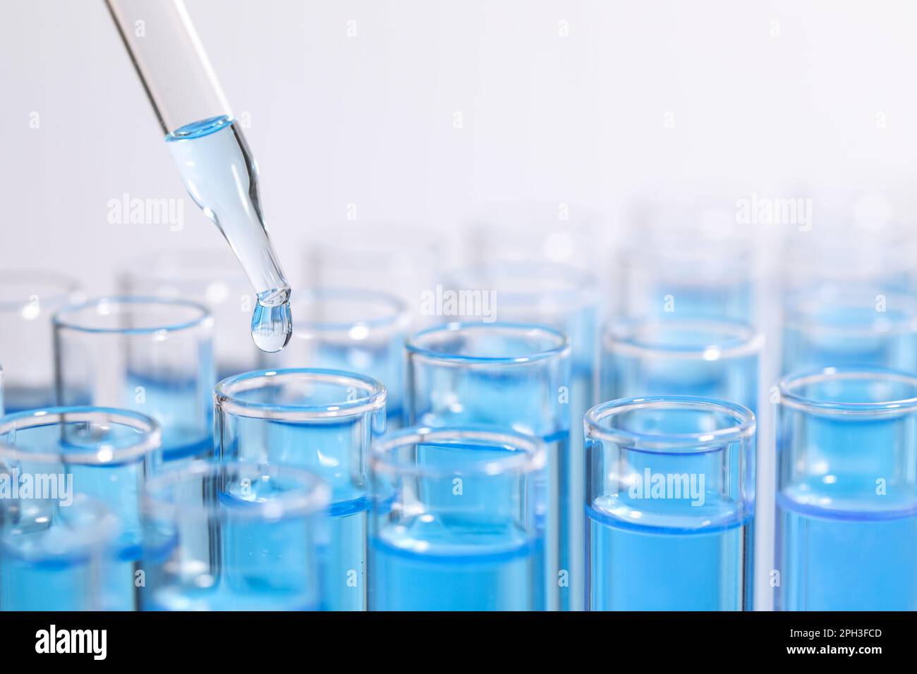 Dripping reagent into test tube on light background, closeup and space ...