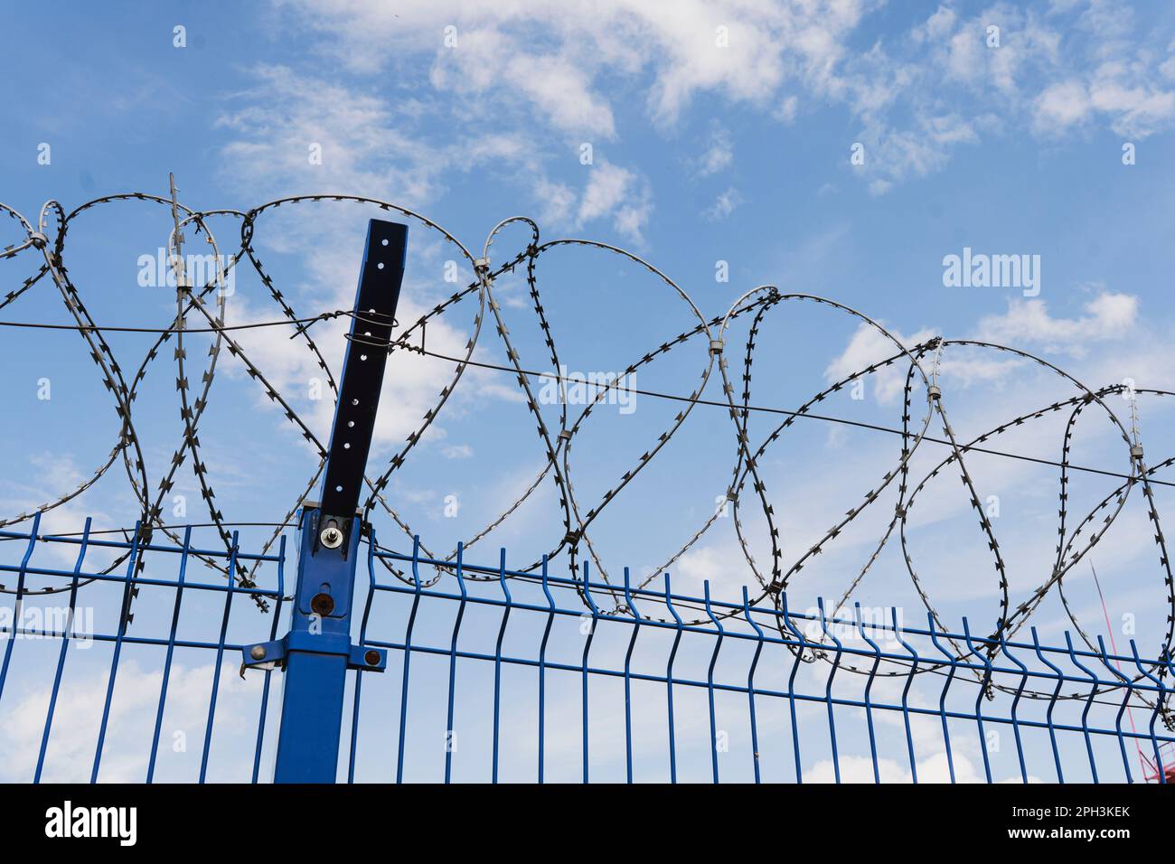 Coiled barbed wire fencing against a blue sky background Stock Photo ...
