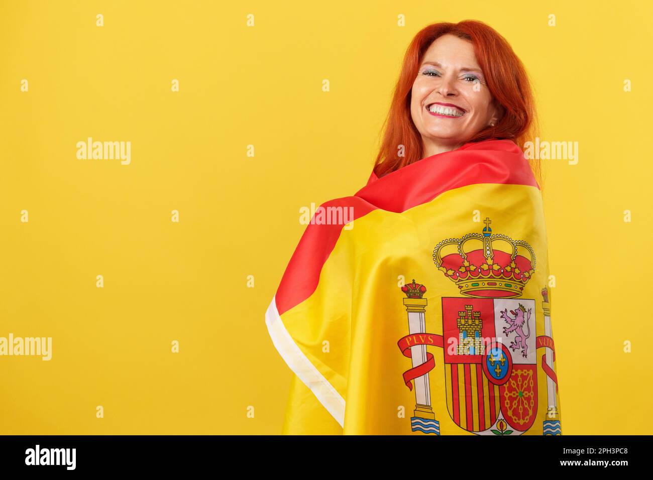 Happy redheaded mature woman wrapping with a spanish national flag ...