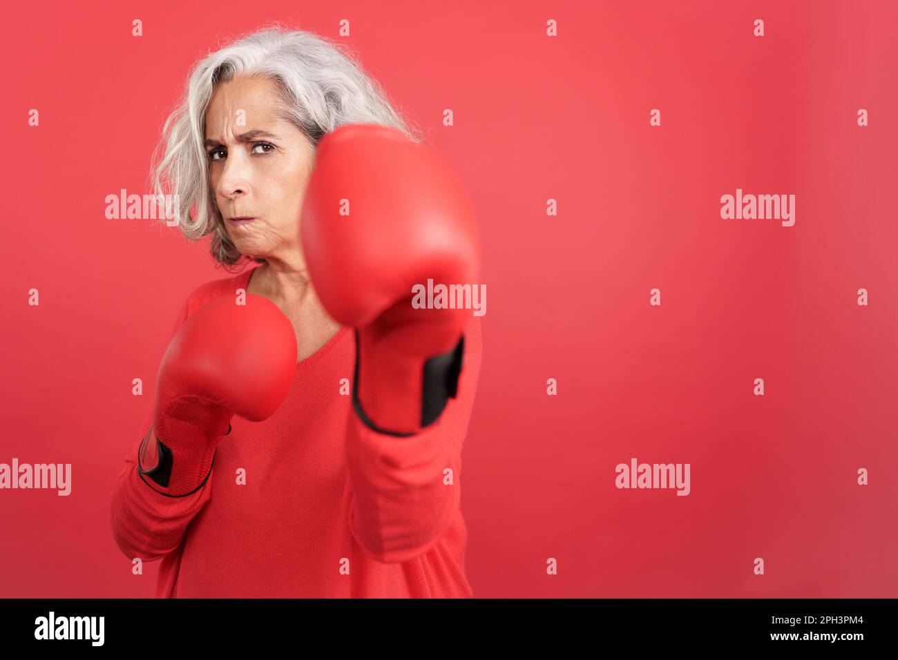 Mature woman in fighting pose wearing boxing gloves Stock Photo - Alamy