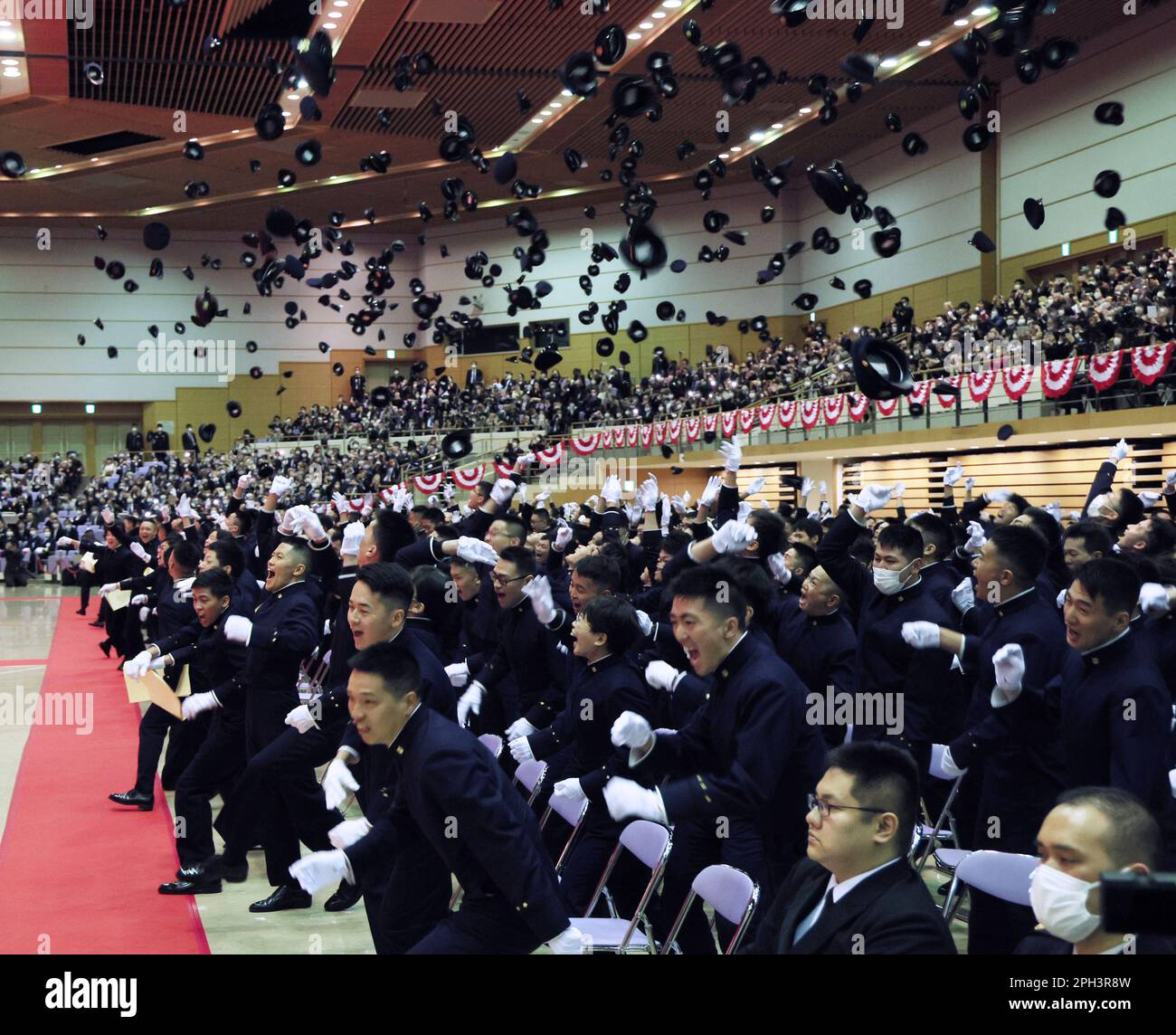 Graduate students throw their caps into the air during a graduation ...