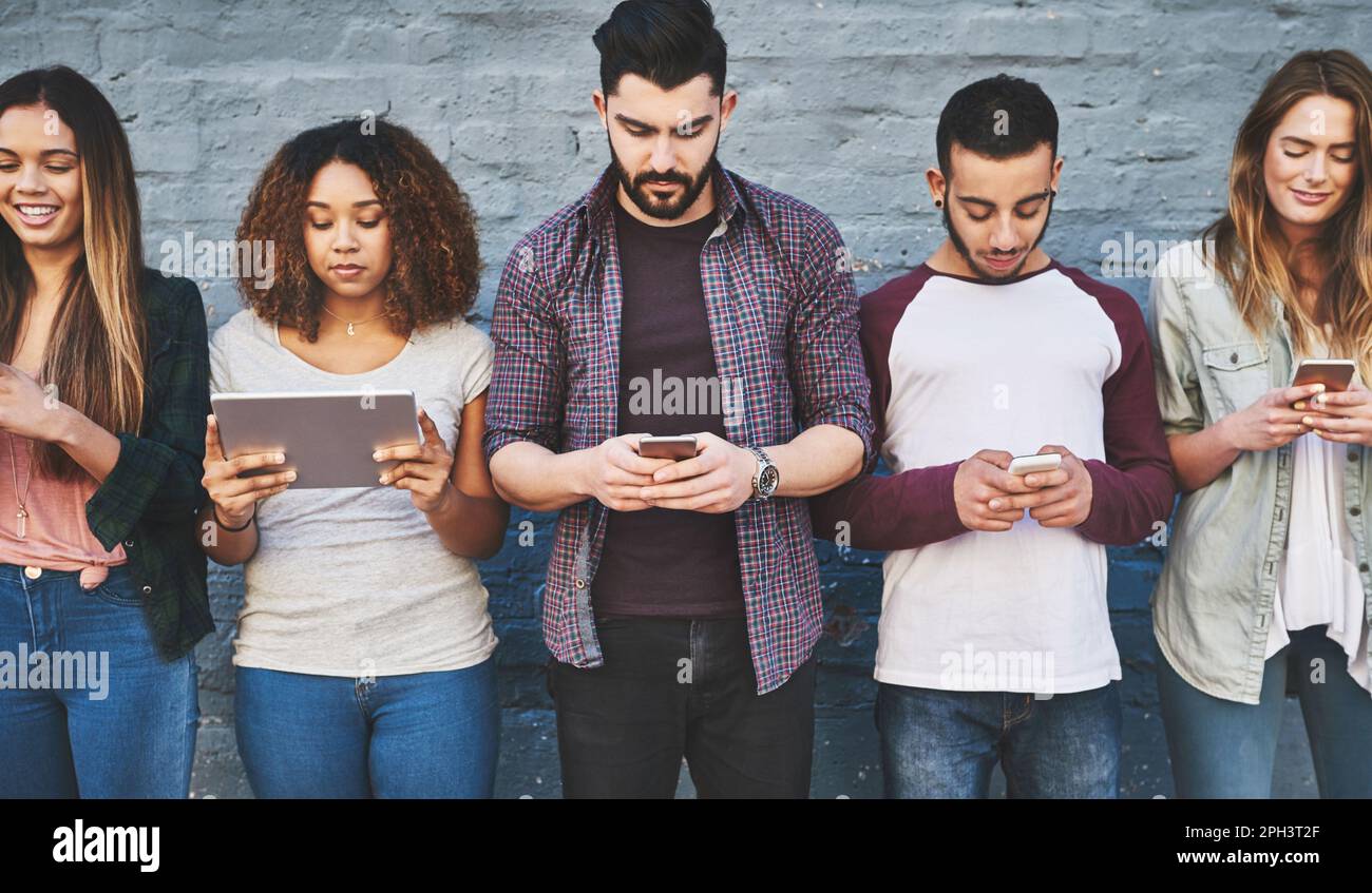 Attached to technology. a group of young friends using their wireless ...