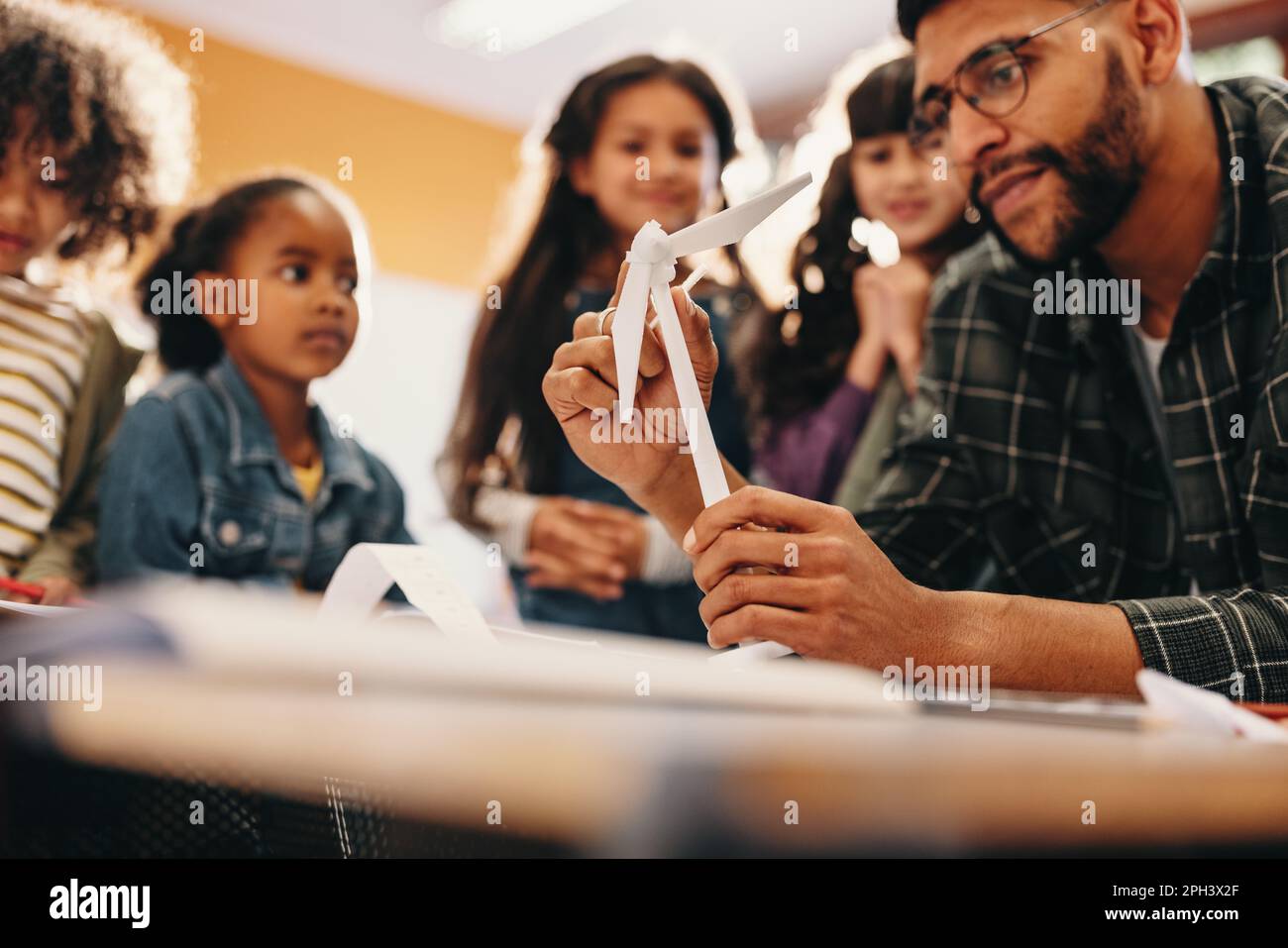 Diverse students stand around a table in a classroom, looking at a 3D ...