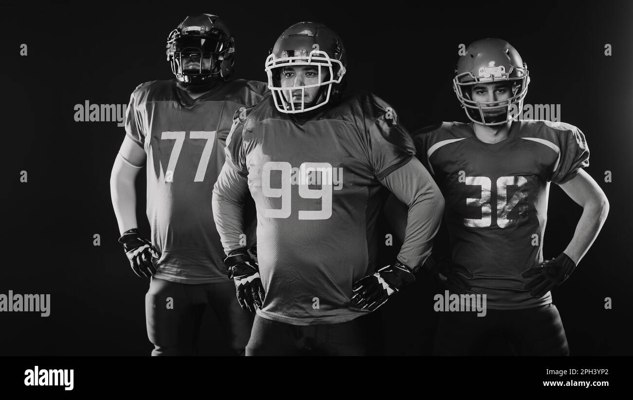 Portrait of three men in uniforms for American football on a black ...