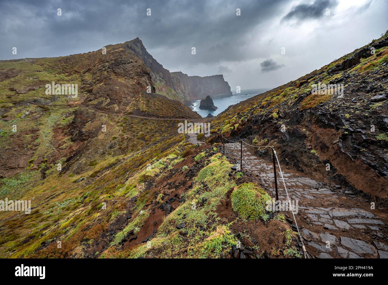 Hiking trail at the rocky promontory, coastal landscape with red cliffs ...