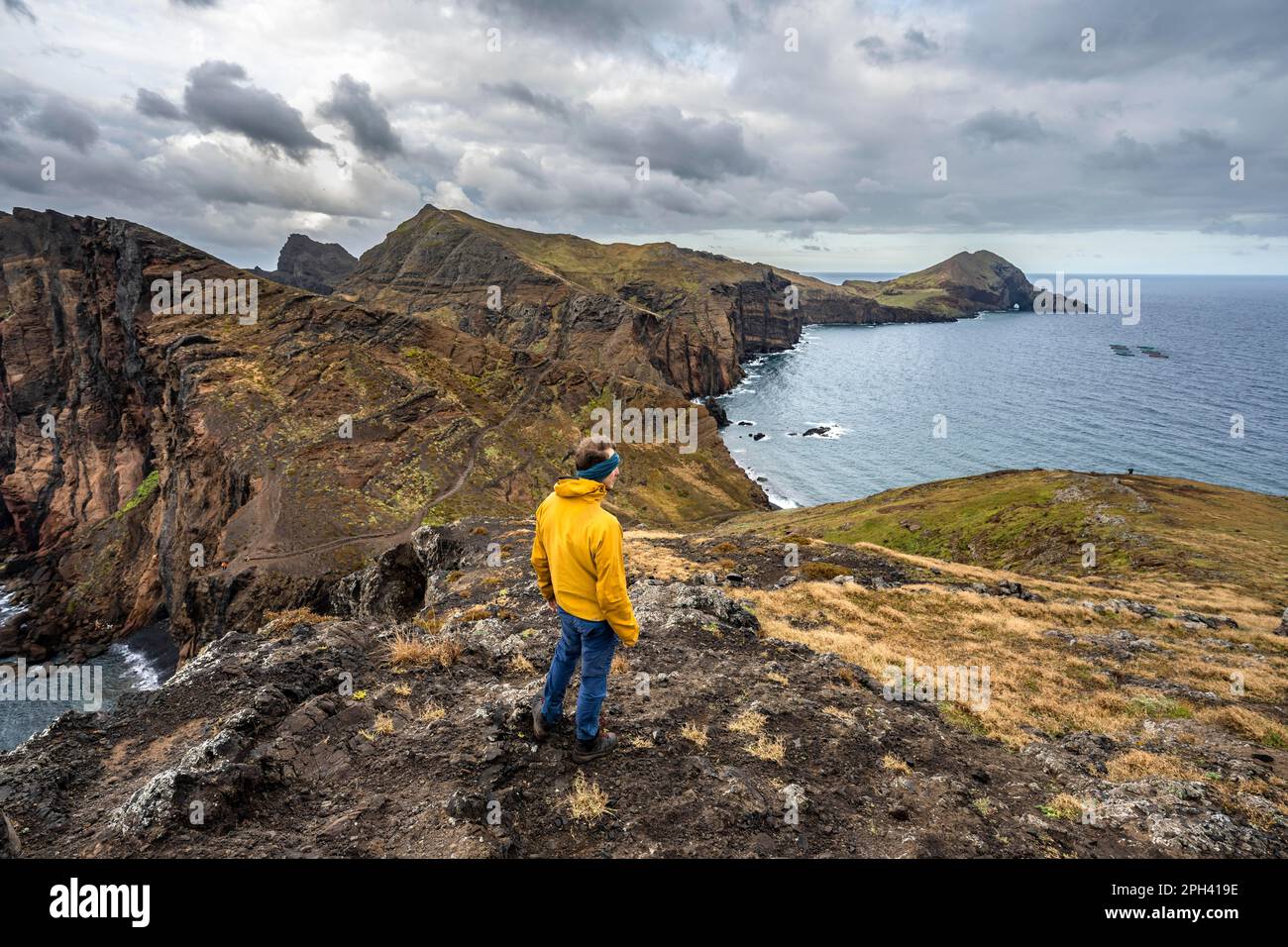 Hikers at the rocky promontory, coastal landscape with red cliffs and ...
