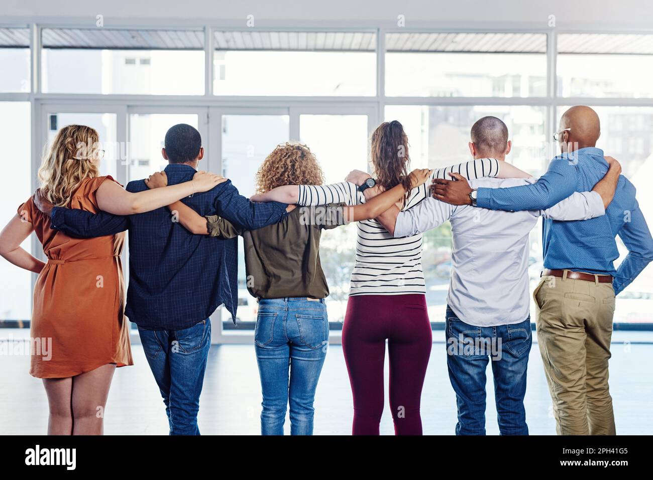 Well always stand together. Rearview shot of a group of people standing ...