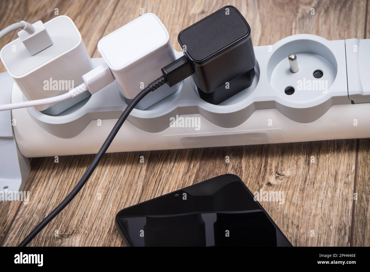 Smartphone, mobile phone and chargers connected to electrical power ...