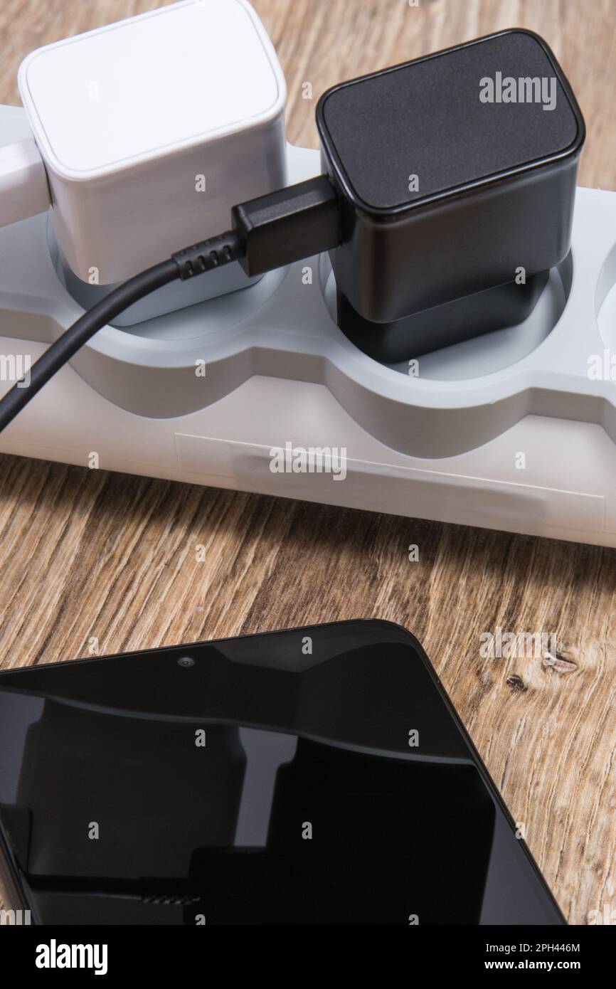Smartphone, mobile phone and chargers connected to electrical power ...