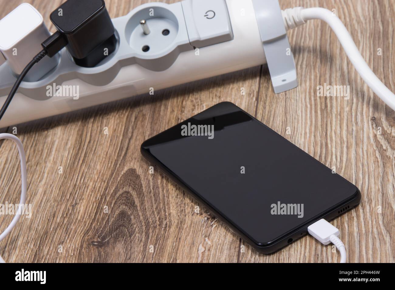 Black smartphone, mobile phone and chargers connected to electrical ...