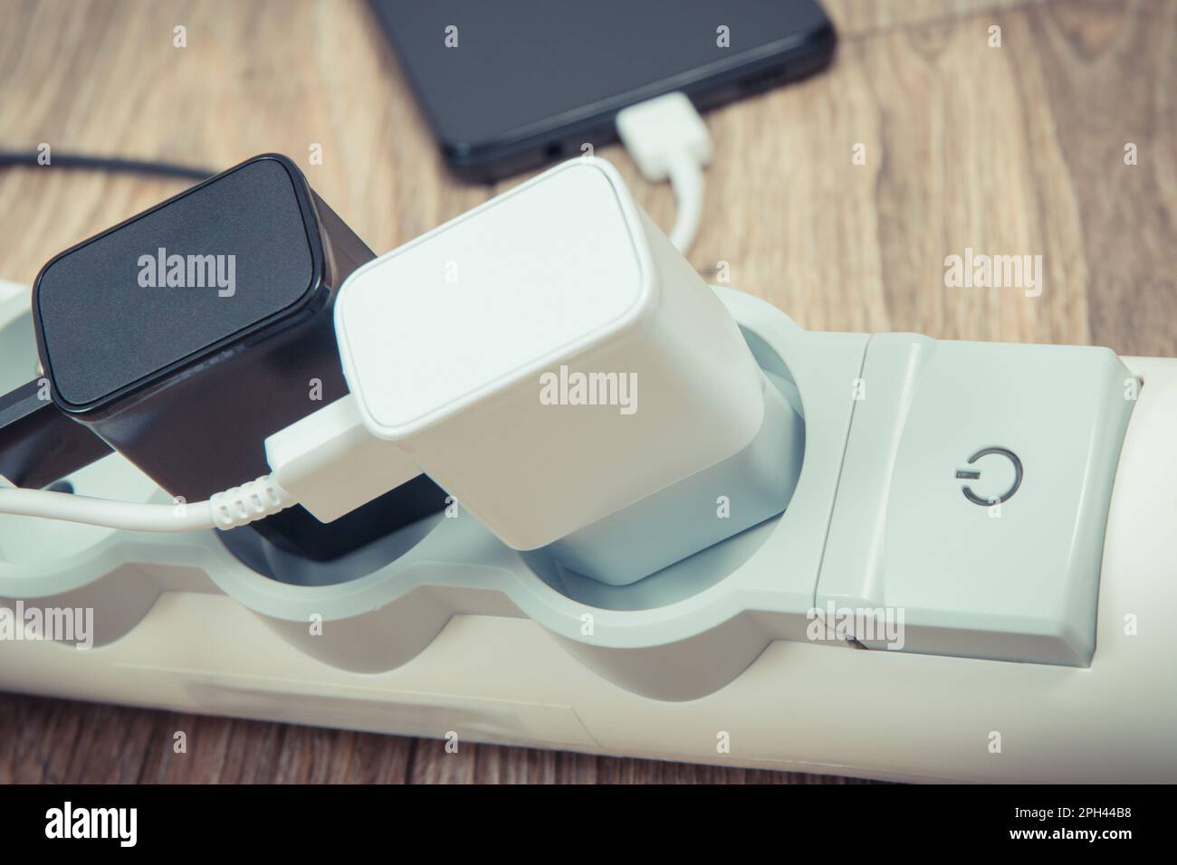 Black smartphone, mobile phone and chargers connected to electrical ...