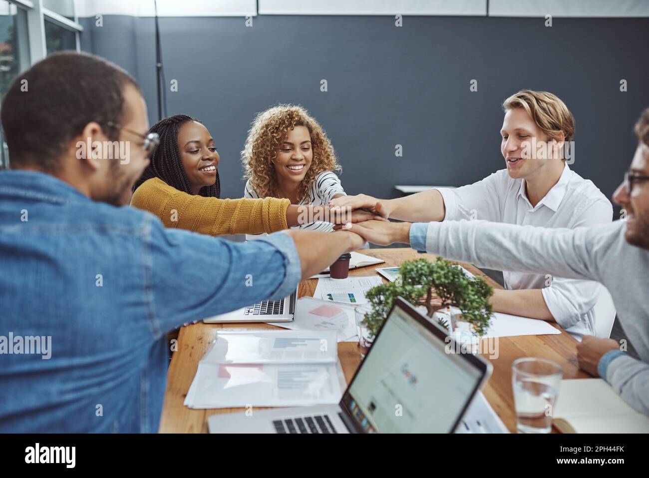All for one. High angle shot of a group of businesspeople joining their ...