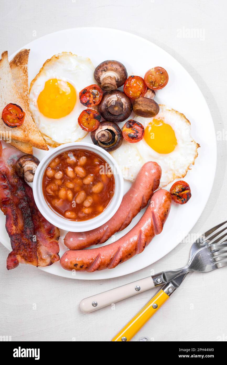 Full english breakfast with fried eggs, tomatoes, sausages, bacon ...