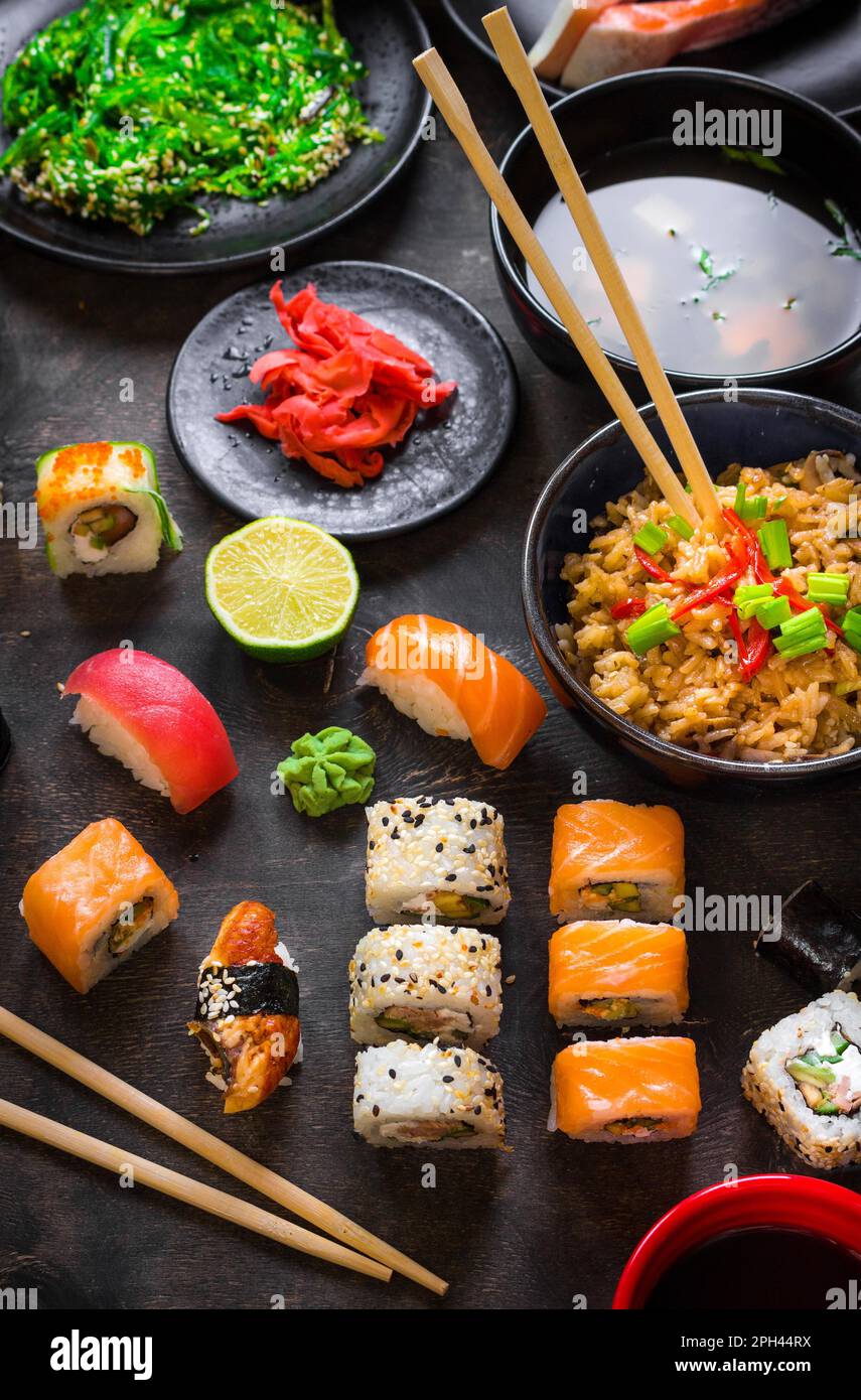 Table served with sushi and traditional japanese food on dark ...