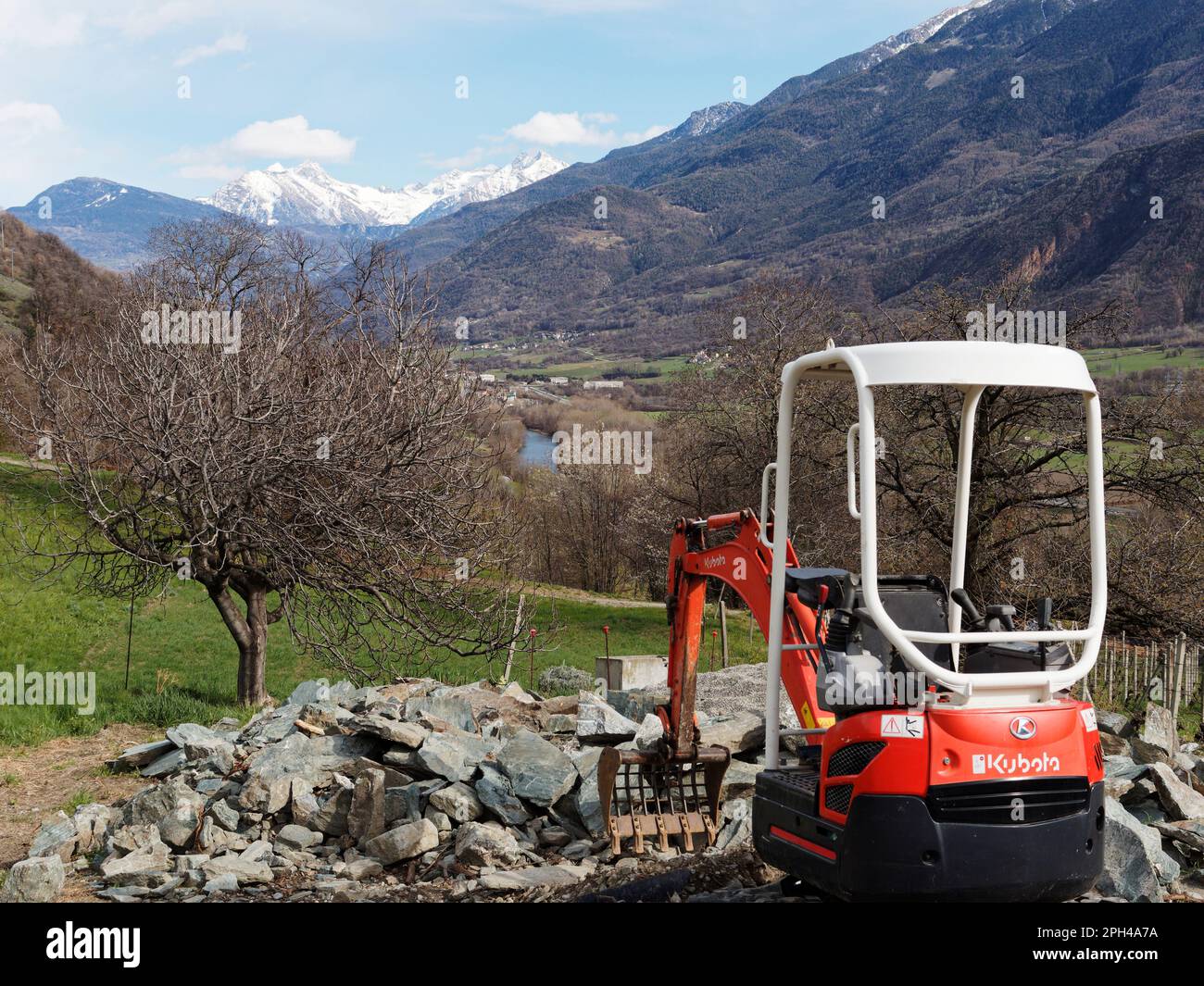 Orange and white digger machine beside a pile of stones in the Aosta ...