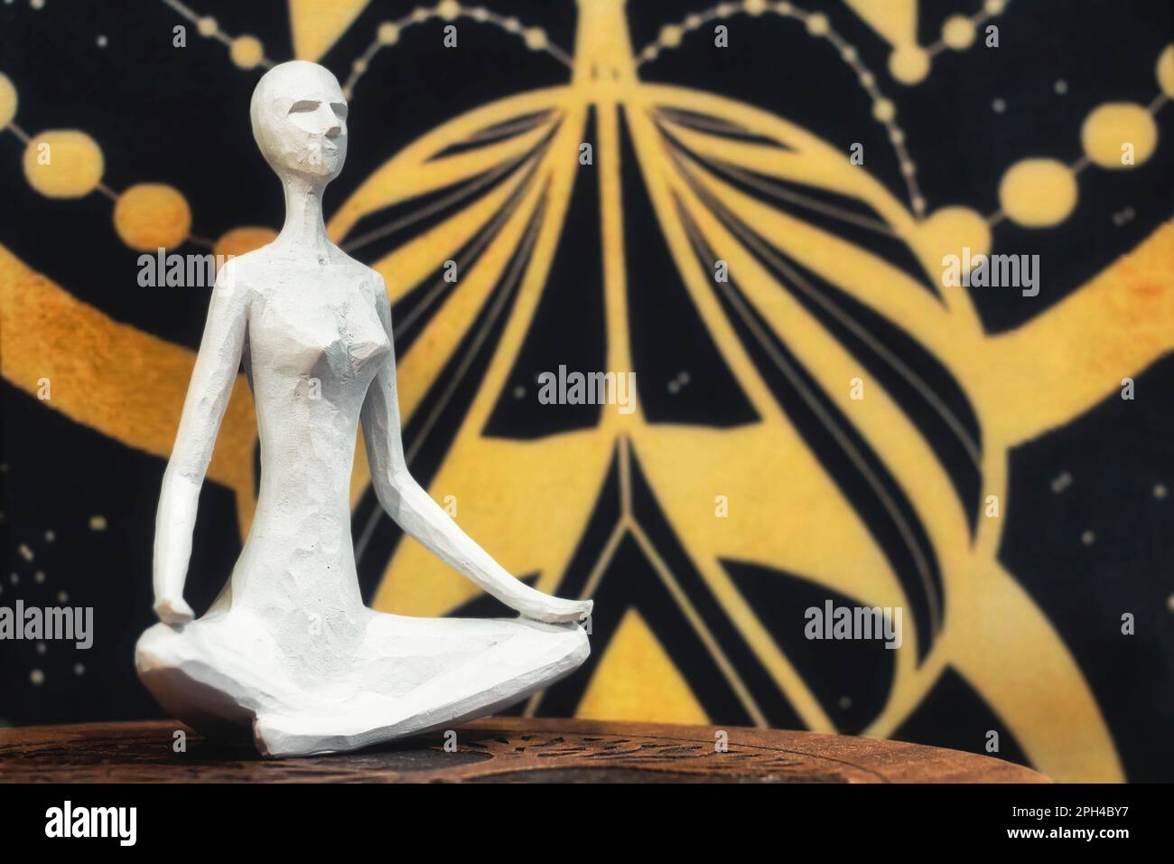 A white wooden statue of a woman sat cross-legged against a karmic ...