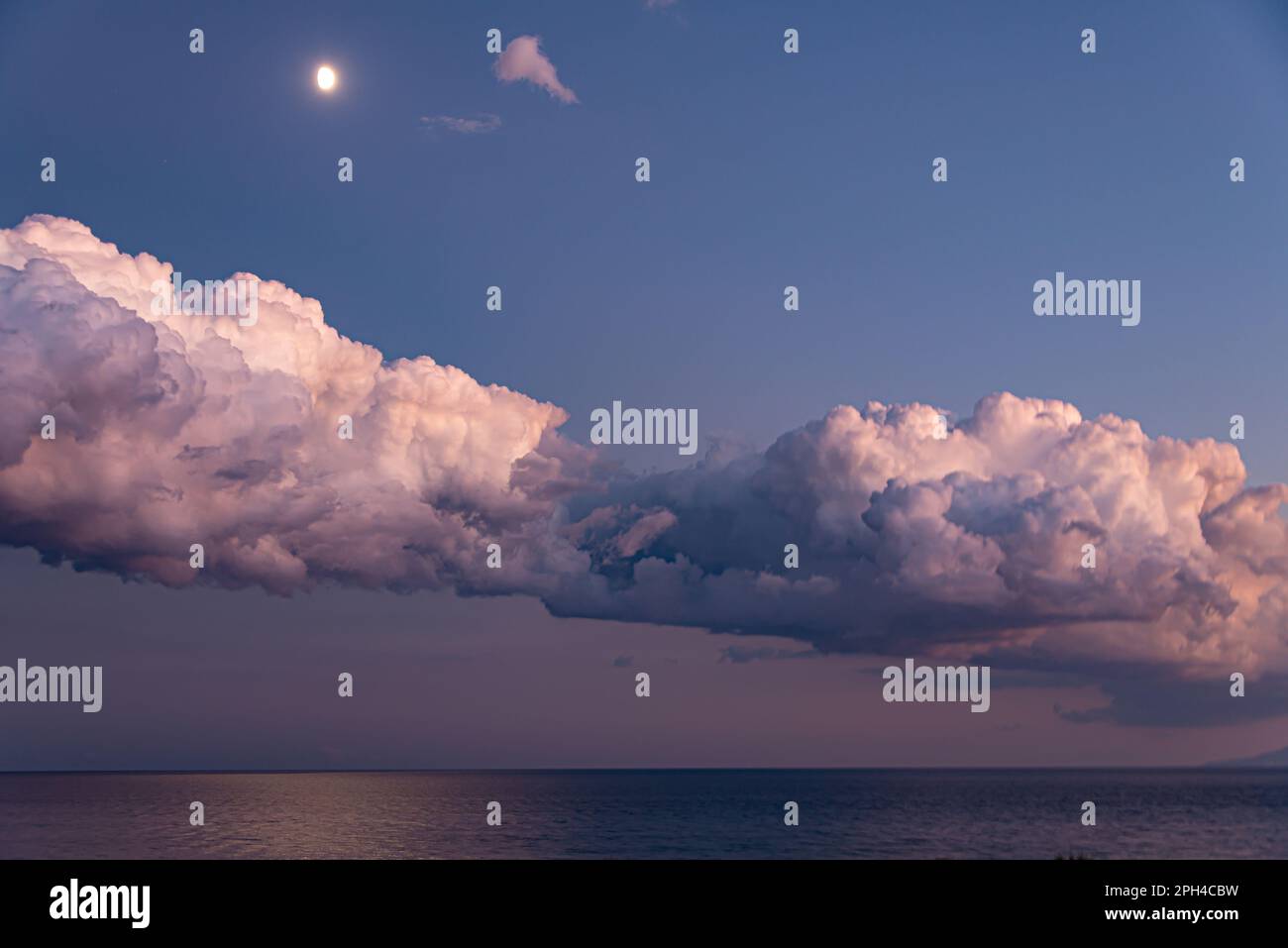 Spectacular moon rise above the ocean waters. Picturesque purple clouds ...