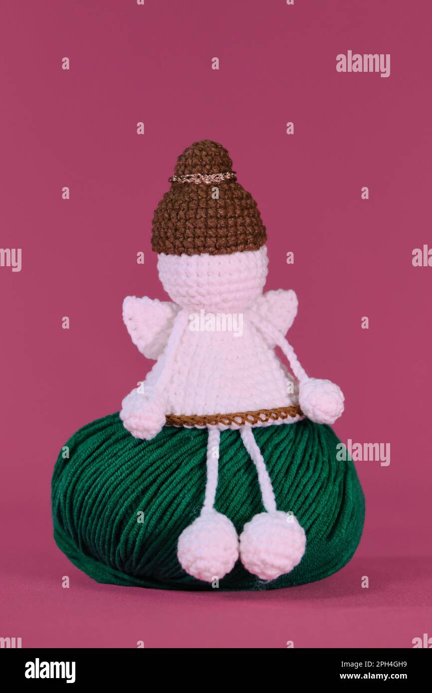 Amigurumi one white angel without face wears brown hat, sits on green ...
