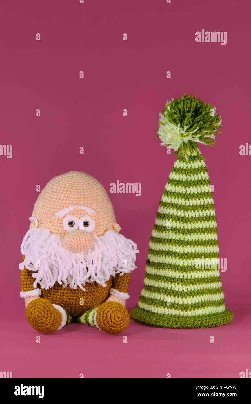 Amigurumi one bald dwarf with green striped hat and white beard on pink ...