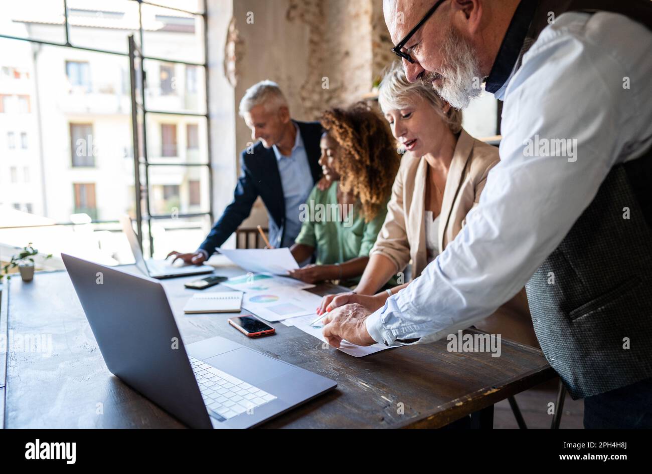 A team of middle-aged professionals are huddled around a conference ...