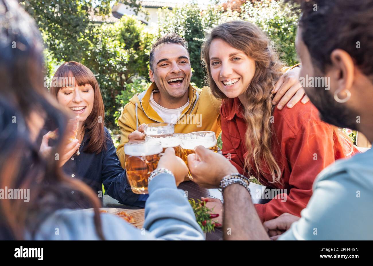 A group of caucasian friends laughing and enjoying cold beers and ...