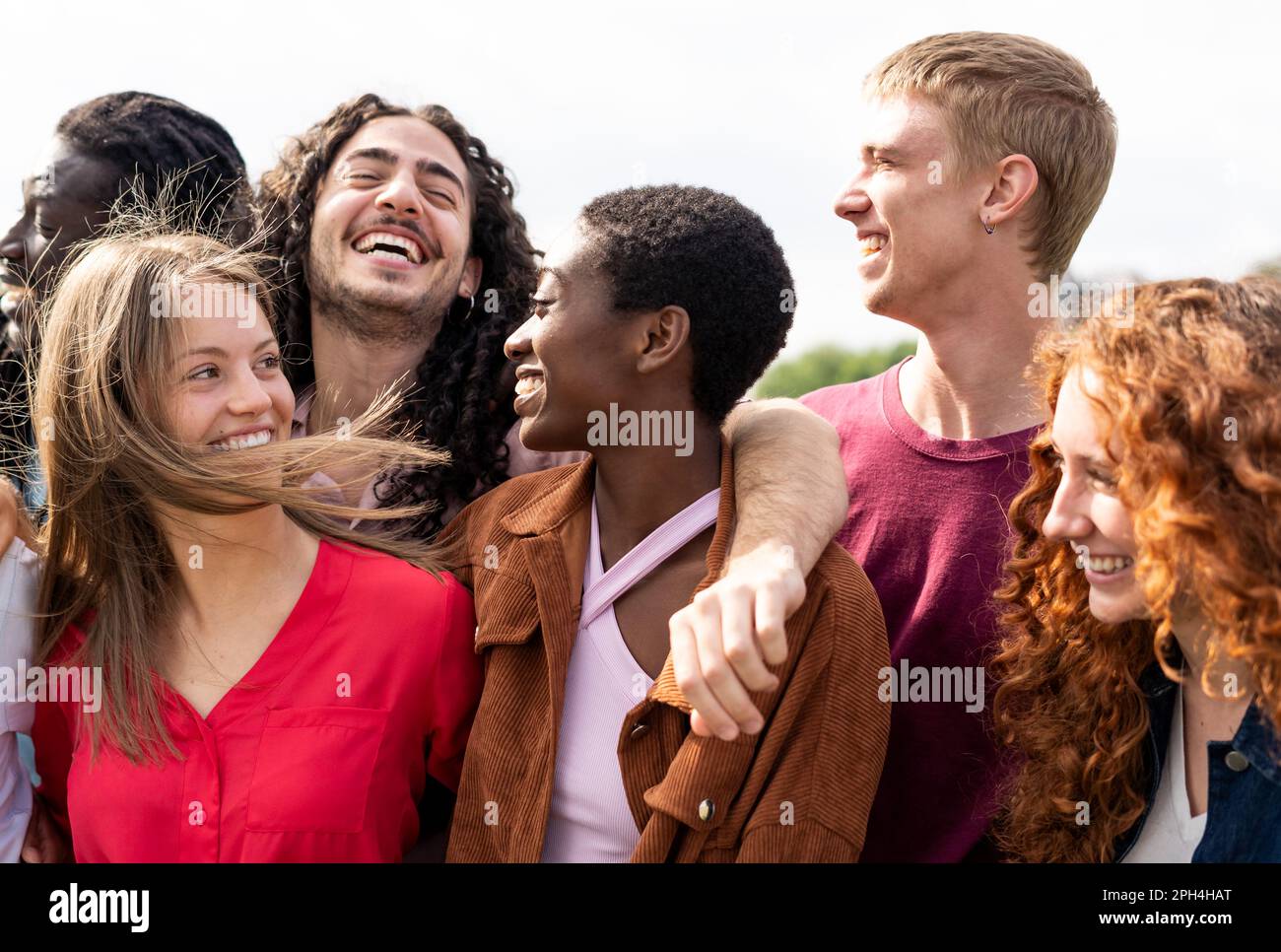 Multiracial group of friends embrace and enjoy a beautiful day together ...