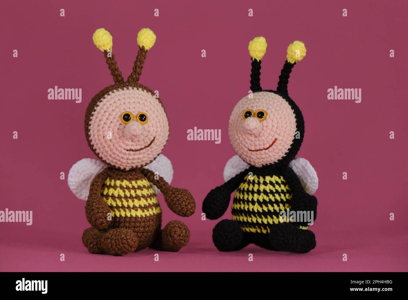 Two bees brown and black with yellow stripes and funny wings and horns ...