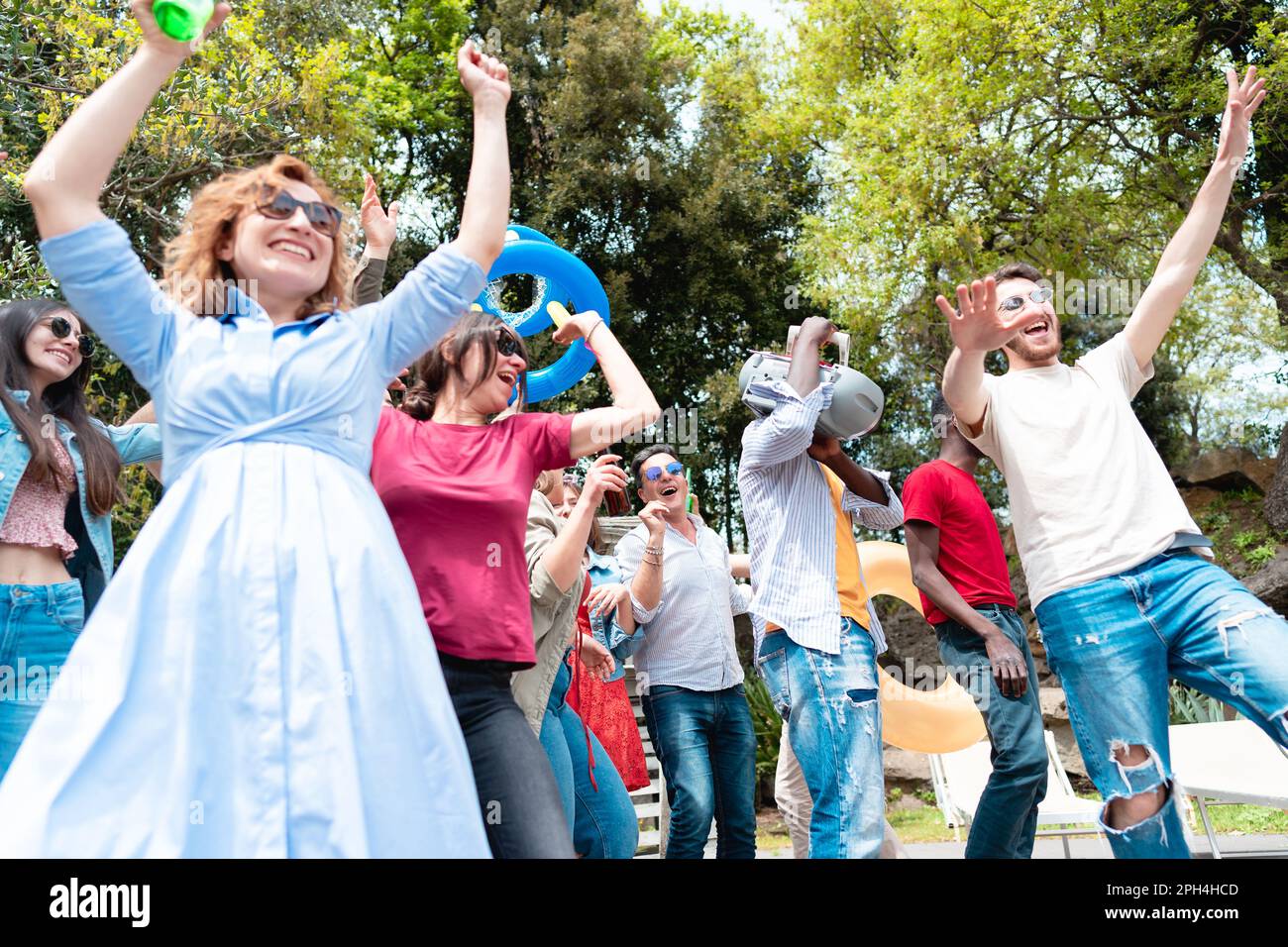 A group of multiracial friends dance and toast to friendship at party ...