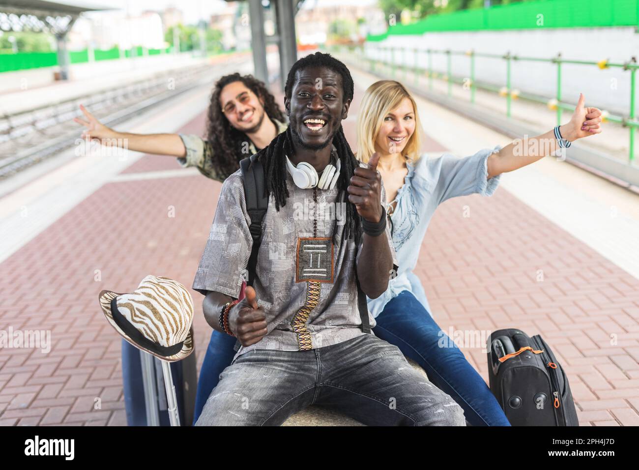 Group of multiracial friends waiting train at station rail as they ...
