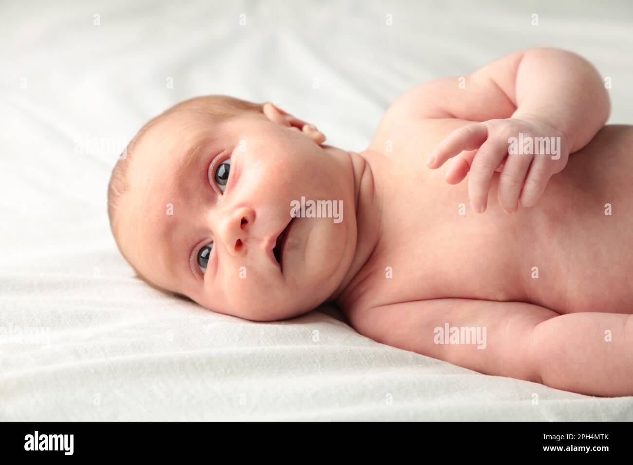 Pretty baby girl lying on white bed, top view Stock Photo - Alamy
