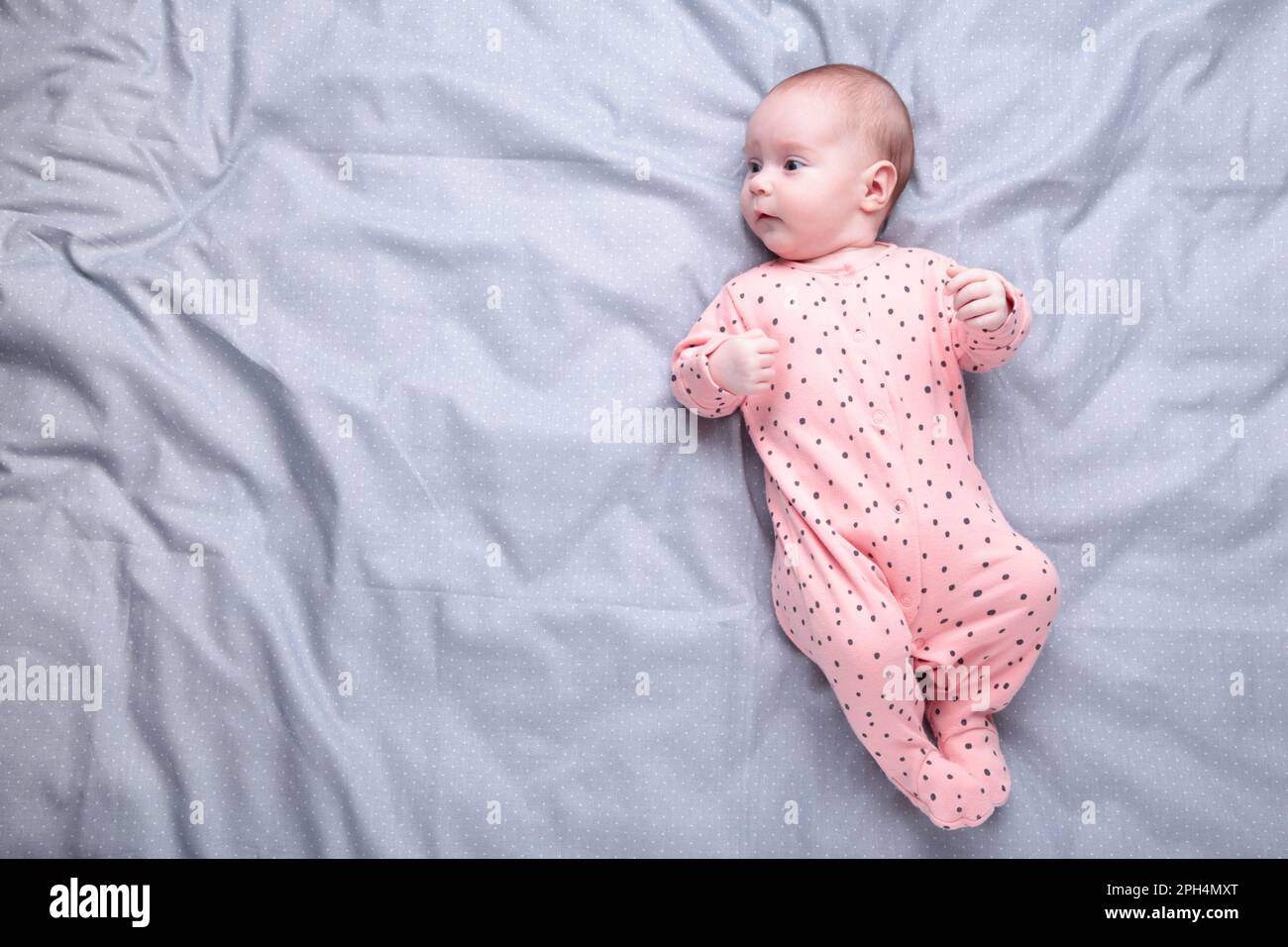Cute baby on the grey bed, top view Stock Photo - Alamy